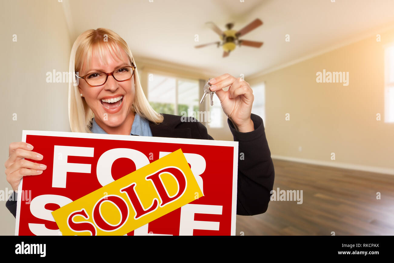 Attractive Young Woman with New Keys and Sold Real Estate Sign In Empty ...