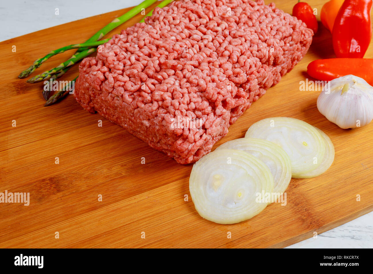 Raw minced meat ingredients on peper with onion, herbs and asparagus ...