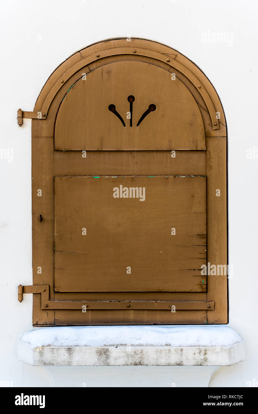 Bespoke dilapidated wood window shutter in arched window on white stone ...