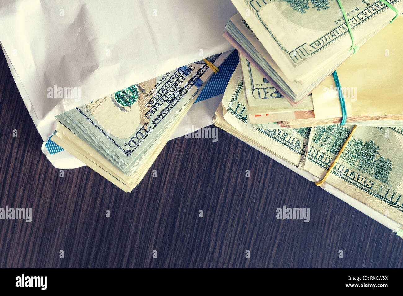 Bundle of american dollar banknotes in white envelope on wooden table ...