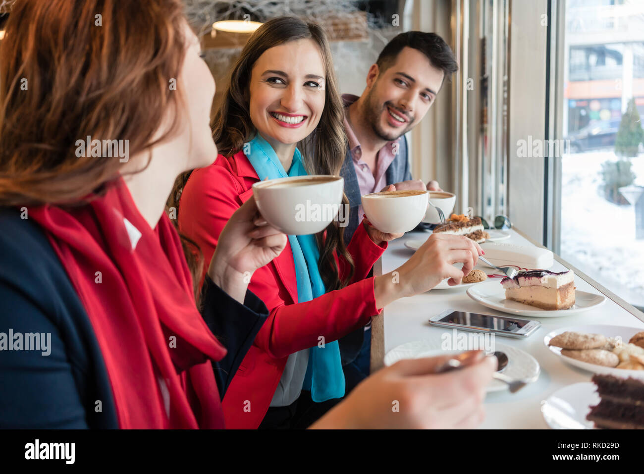 Colleagues smiling while eating delicious cakes during break in a ...
