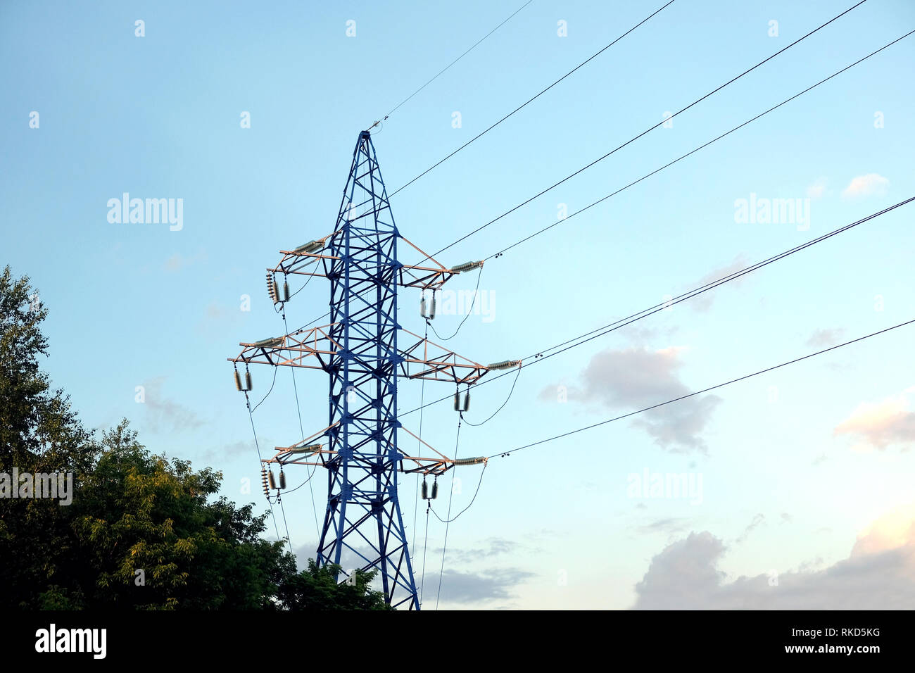 High-voltage power line metal pylon with wires over cloudy blue sky on ...