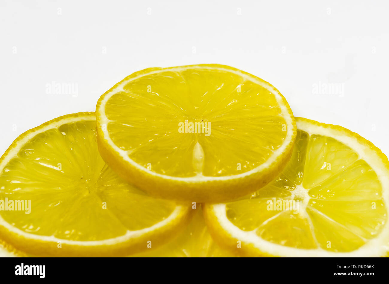 Thinly sliced lemon wedges lie on a white background with copy space ...