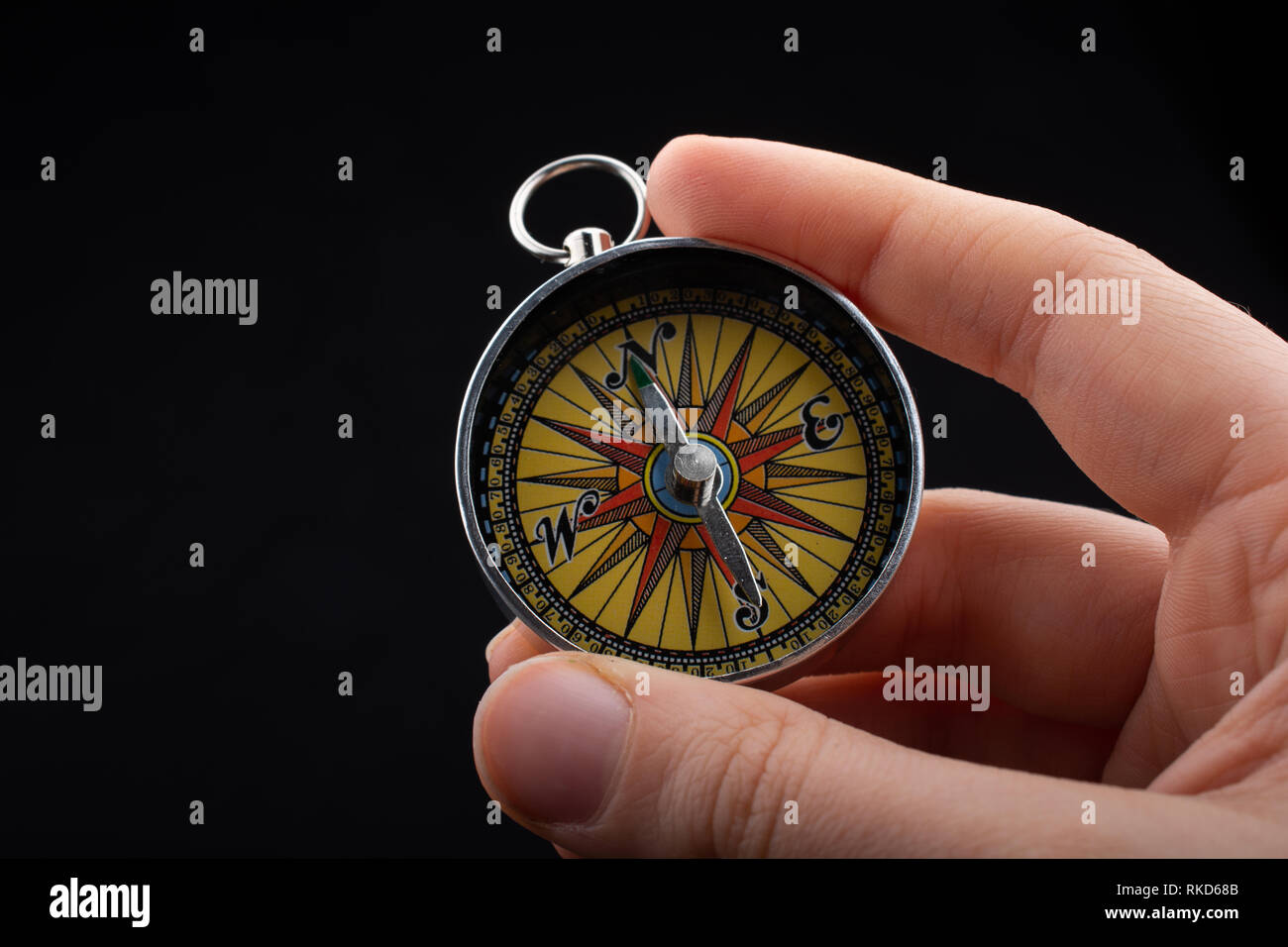 Hand is holding a magnetic compass on black background Stock Photo - Alamy