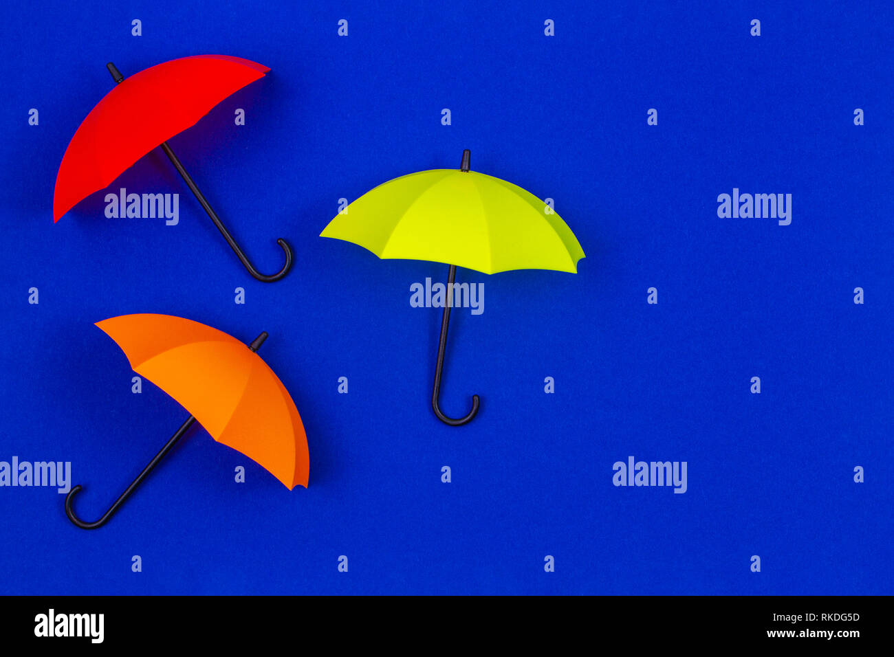 Small colorful umbrellas on blue color background Stock Photo - Alamy
