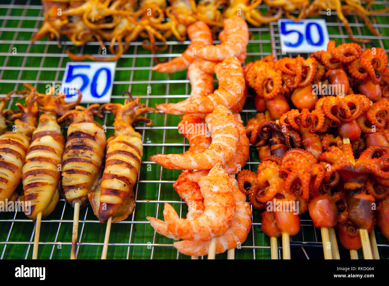 An arrangement of skewered grilled seafood consisting of squid, octopus ...
