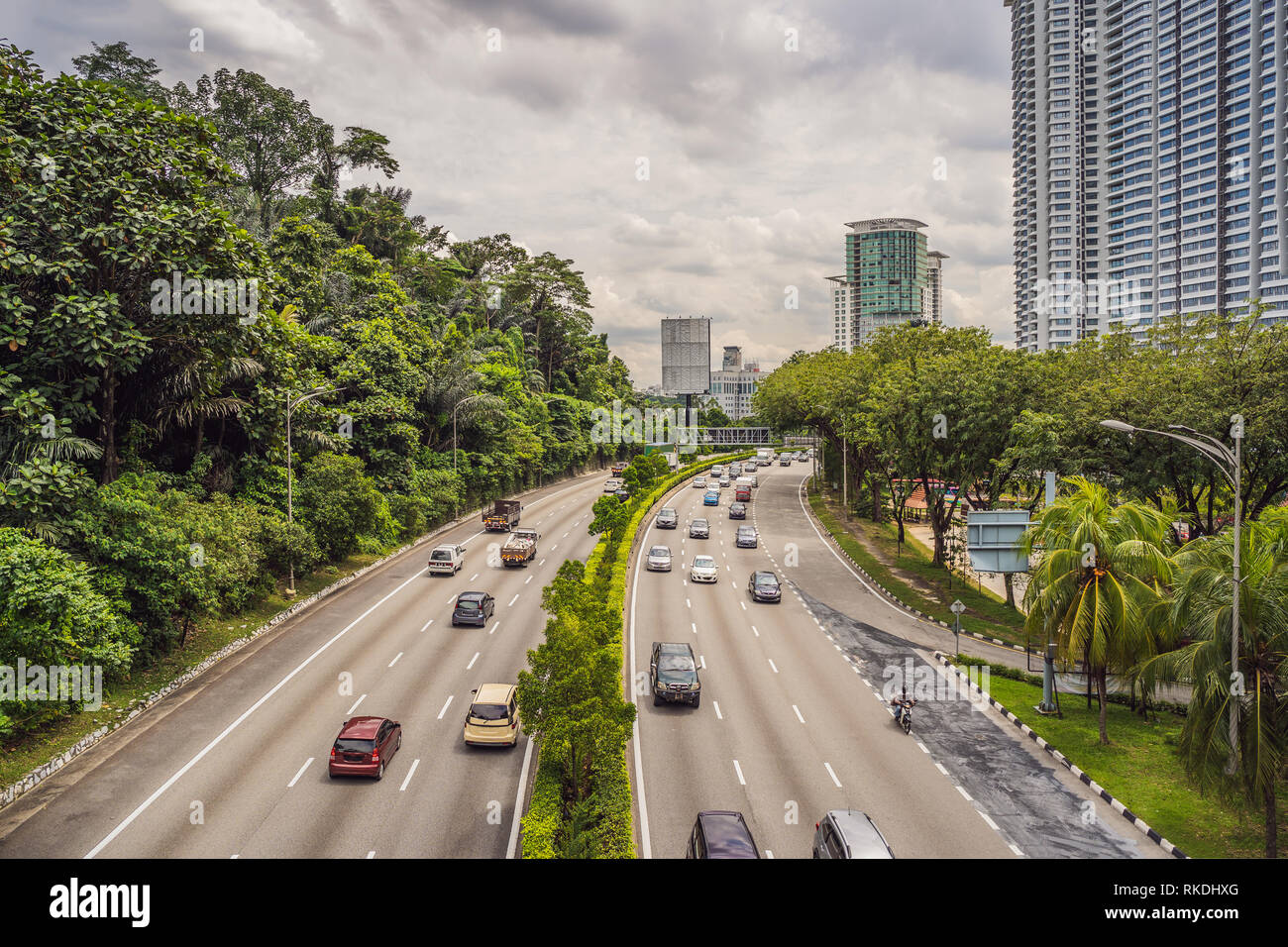 Highway with cars surrounded by greenery and skyscrapers Stock Photo ...