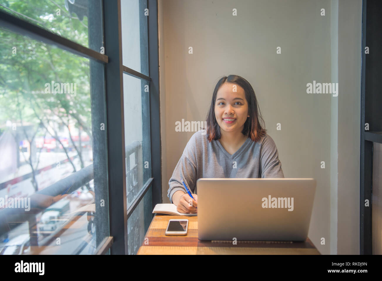 Smiling young Asian student writing notes Stock Photo - Alamy