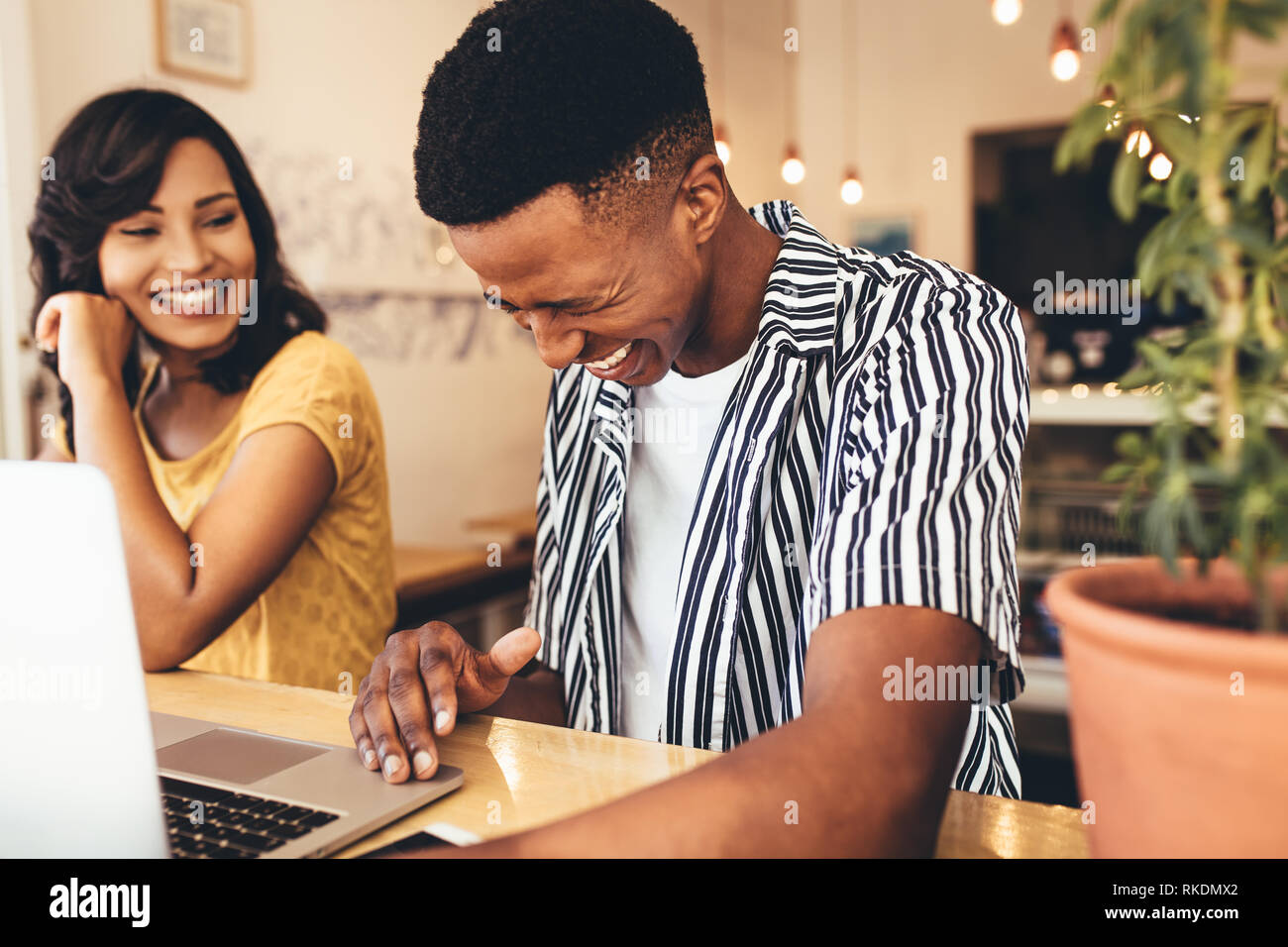 Young man smiling while talking with female friend at coffee shop. Two ...