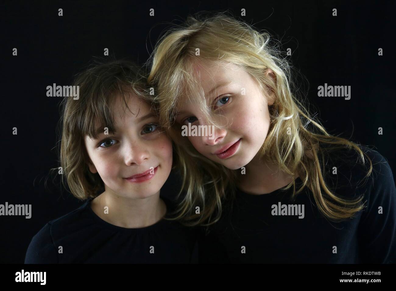 Two young girls putting their heads together for a portrait against a ...