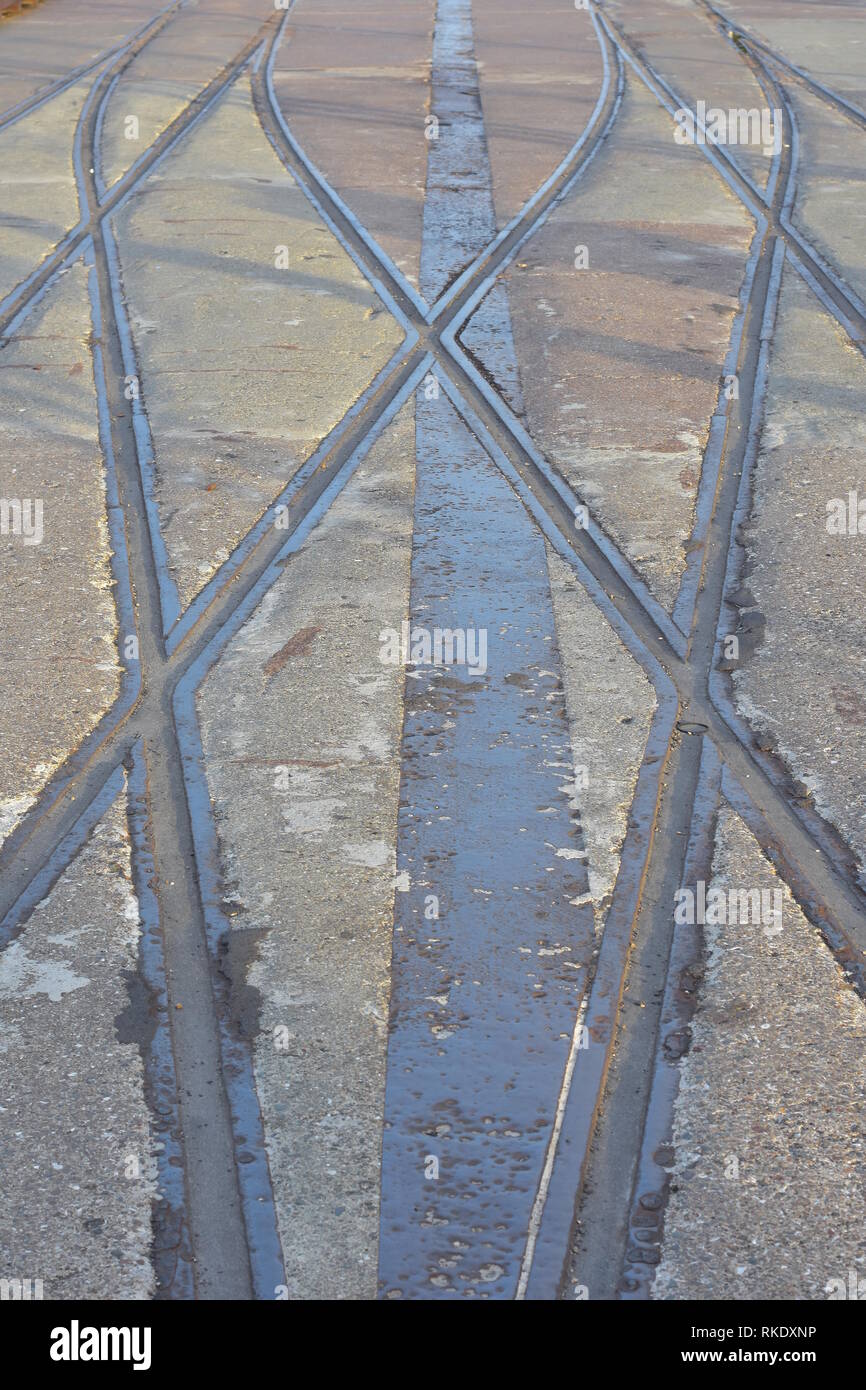 Unused interlaced tramway tracks with rusty and dented edges on paved ...