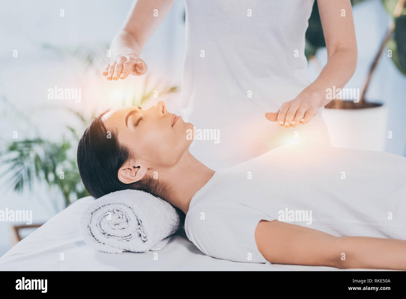 side view of calm young woman receiving reiki healing therapy on head ...