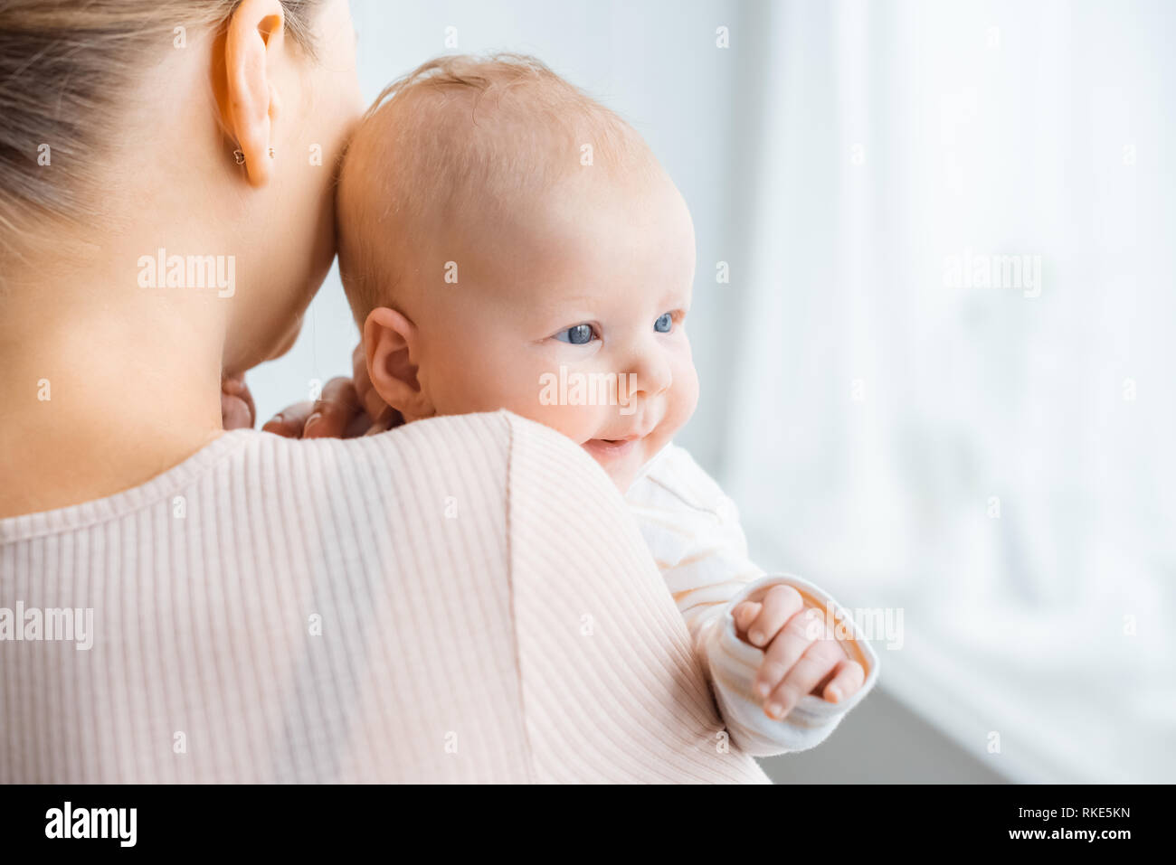 back view of young mother carrying adorable baby at home Stock Photo ...
