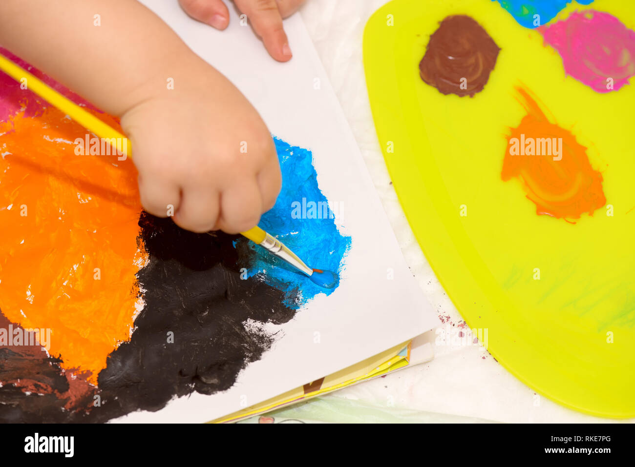 Child's hand holding a paintbrush and painting Stock Photo - Alamy
