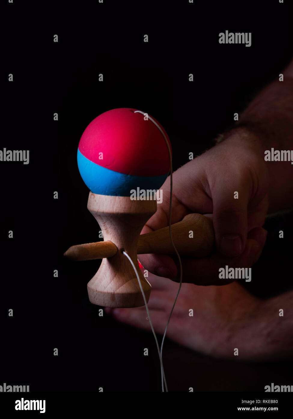 Classic Japanese game kendama on black background. Two boys hands ...