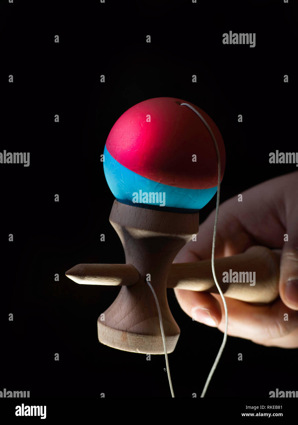 Classic Japanese game kendama on black background. Two boys hands ...