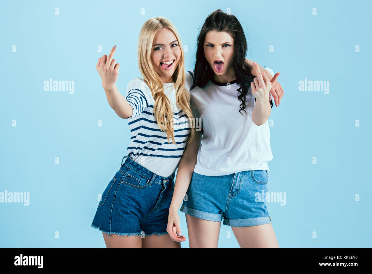 Stylish girls showing middle fingers isolated on blue Stock Photo - Alamy