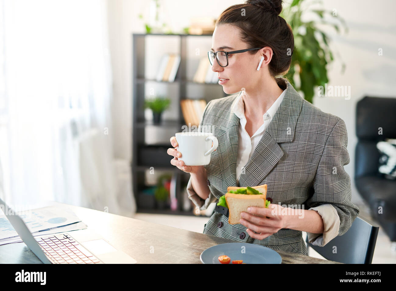 Businesswoman Eating Lunch at Workplace Stock Photo - Alamy