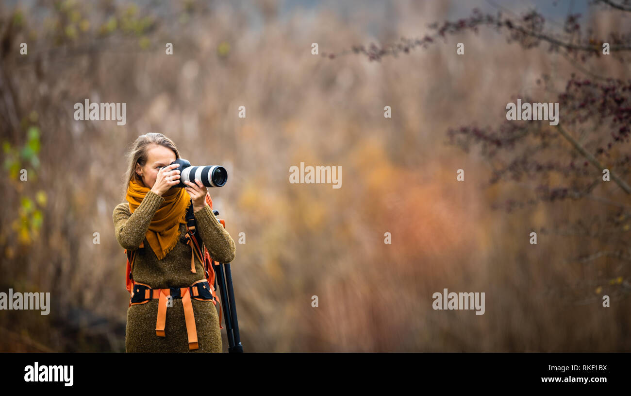 Pretty, female photographer taking pictures outdoor on a lovely autumn ...