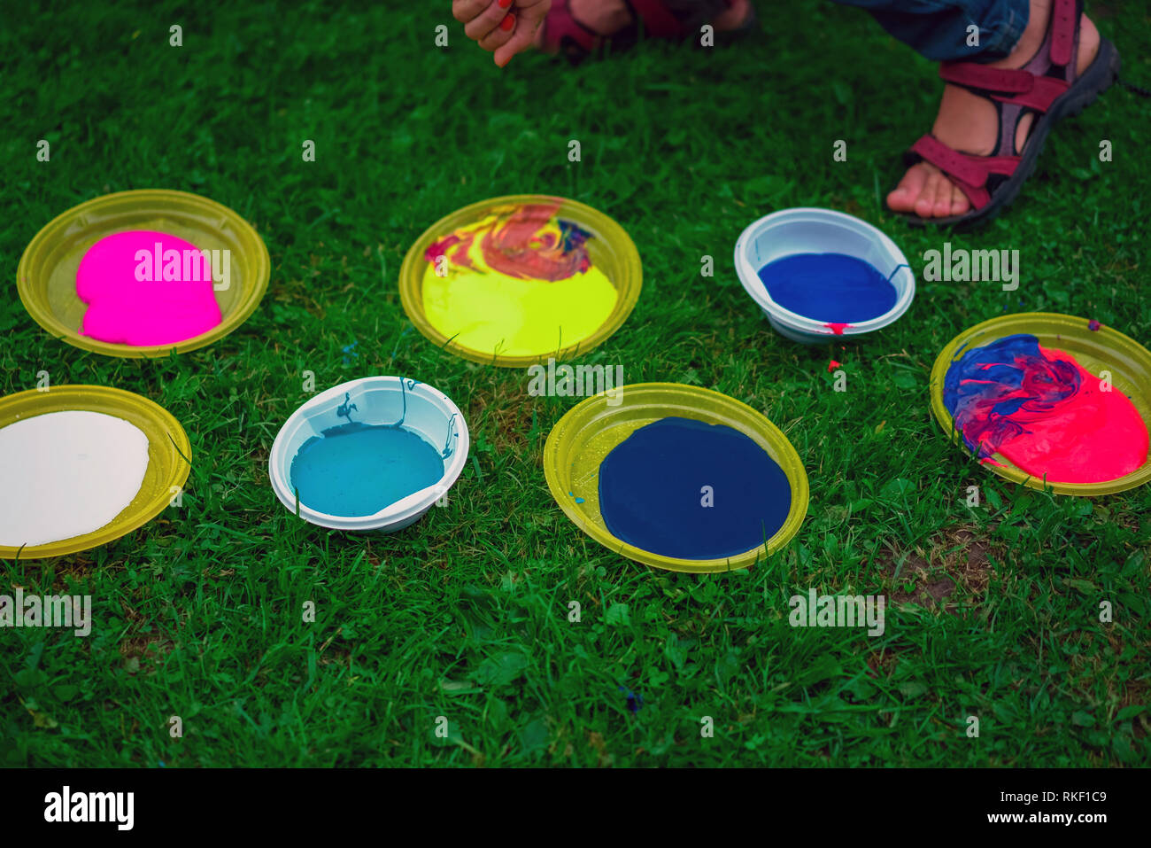 yellow plates on the green grass with different acrylic paint in ...