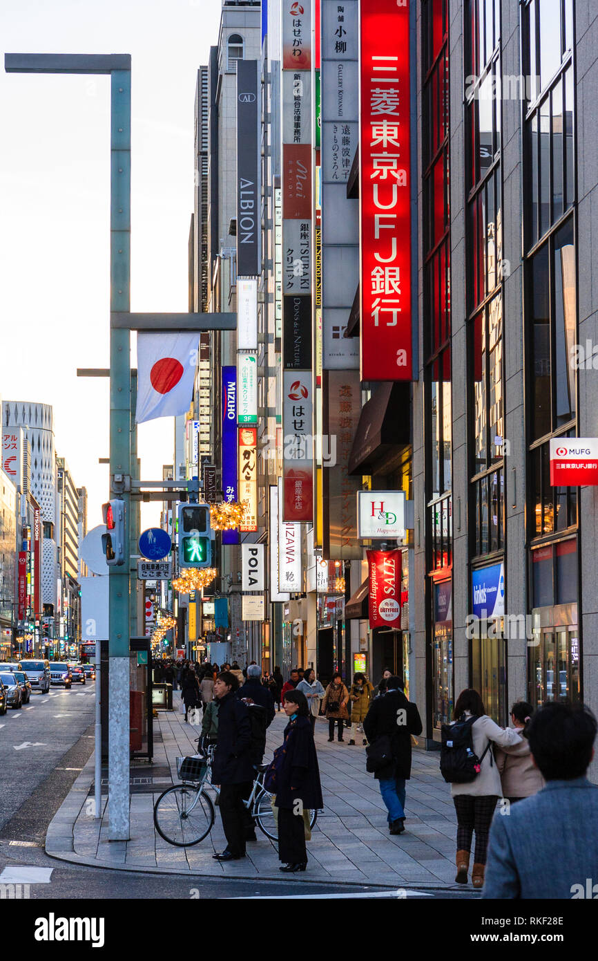 Tokyo, Ginza, golden hour. View along pavement, high rise stores and ...