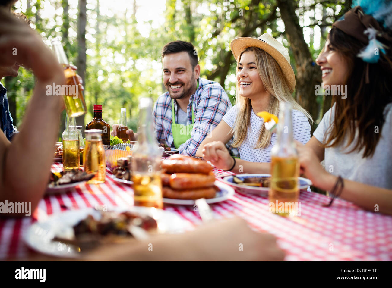 Group of happy friends eating and drinking beers at barbecue dinner ...