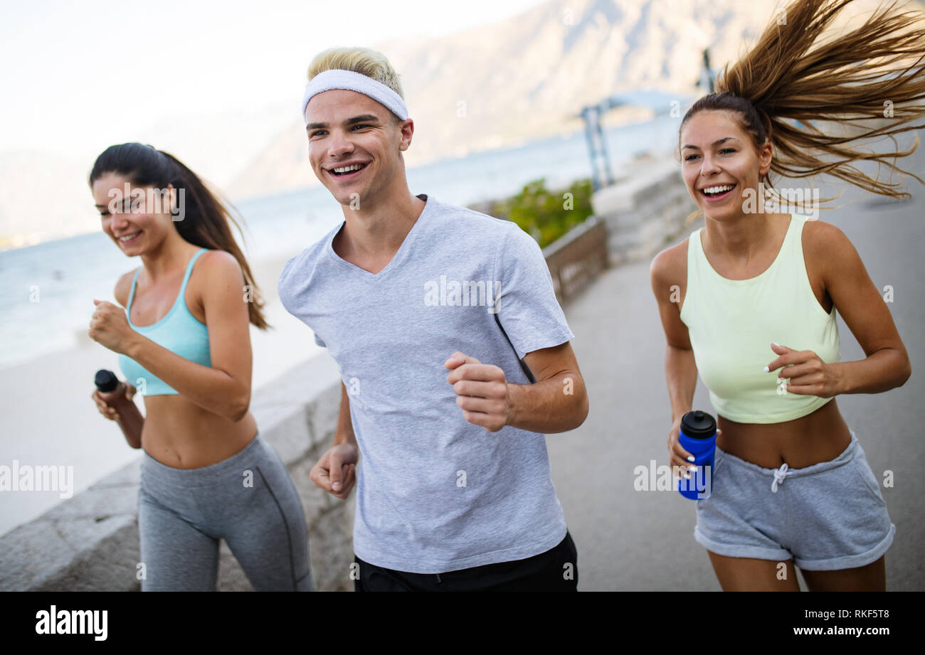 Happy fit people running and jogging together in summer sunny nature ...