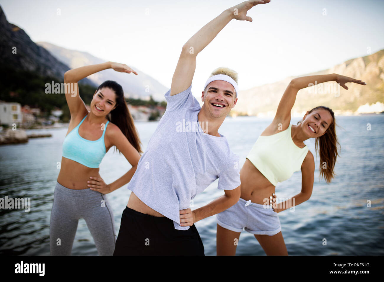 Fit group of happy people exercising outdoor. Smiling friends doing ...