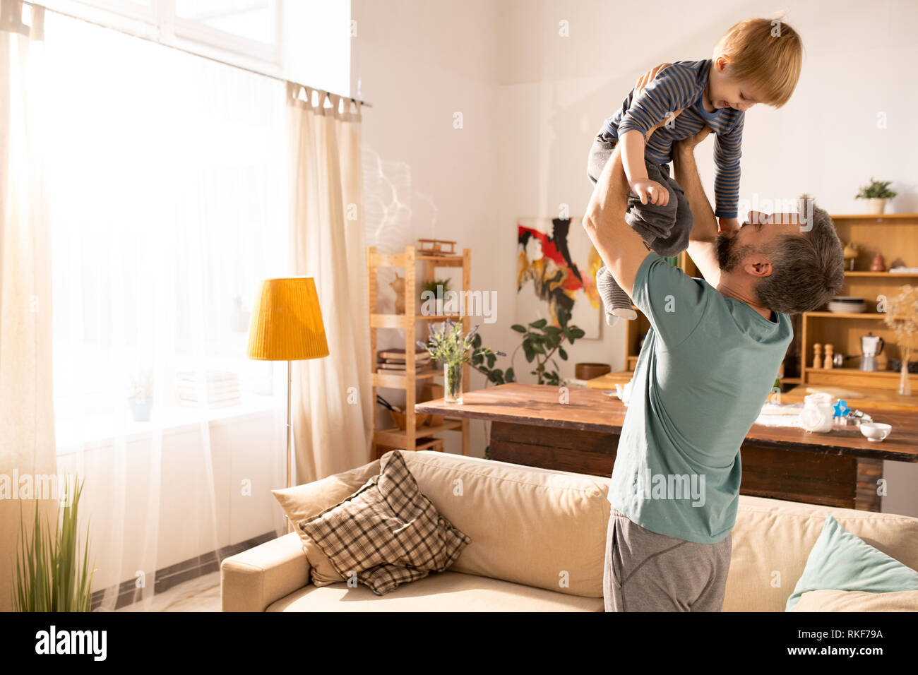 Happy father raising son at cozy home Stock Photo - Alamy