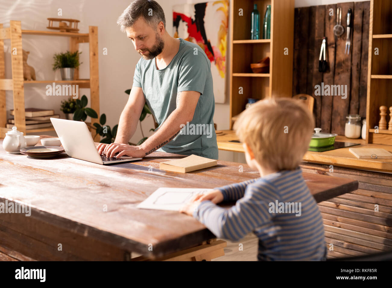 Busy father working while sad son looking at him Stock Photo - Alamy