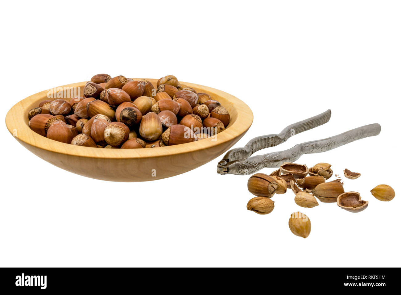 Wooden bowl with hazelnuts, nutcracker and opened nuts isolated on ...