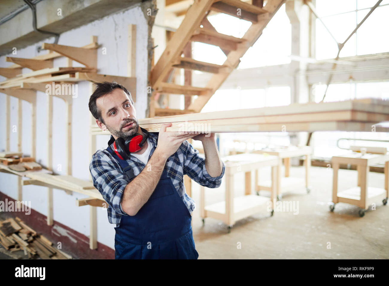 Builder carrying wooden planks Stock Photo - Alamy