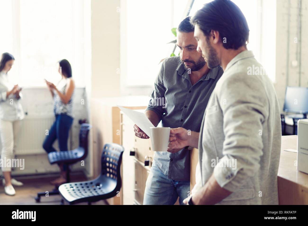 Nice coffee break. Two cheerful young people holding coffee cups and ...