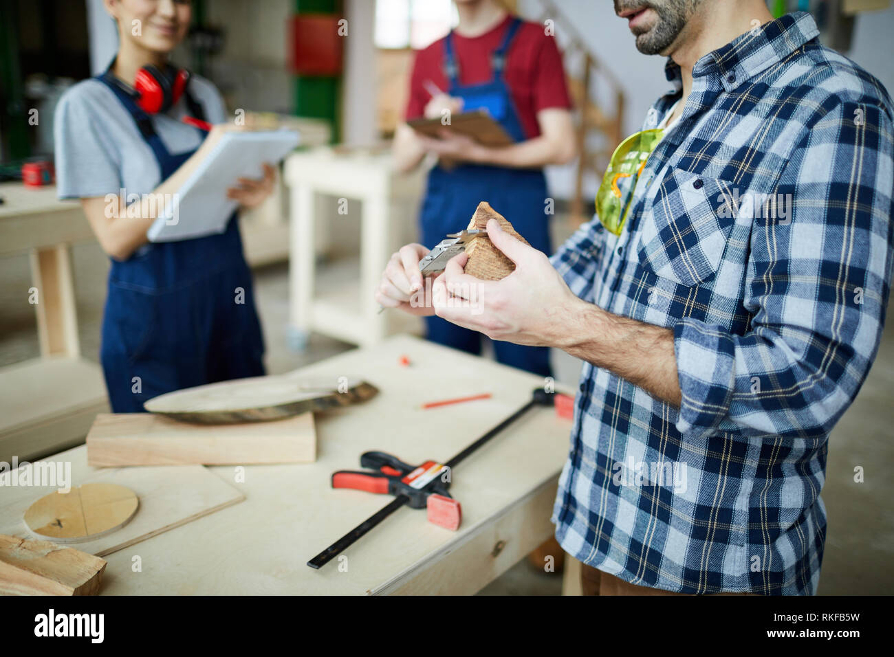 Measuring distance between opposite sides of wooden piece with caliper ...