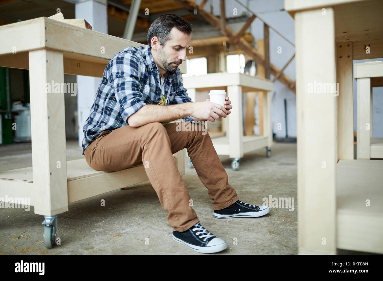 Sad carpenter drinking coffee Stock Photo - Alamy