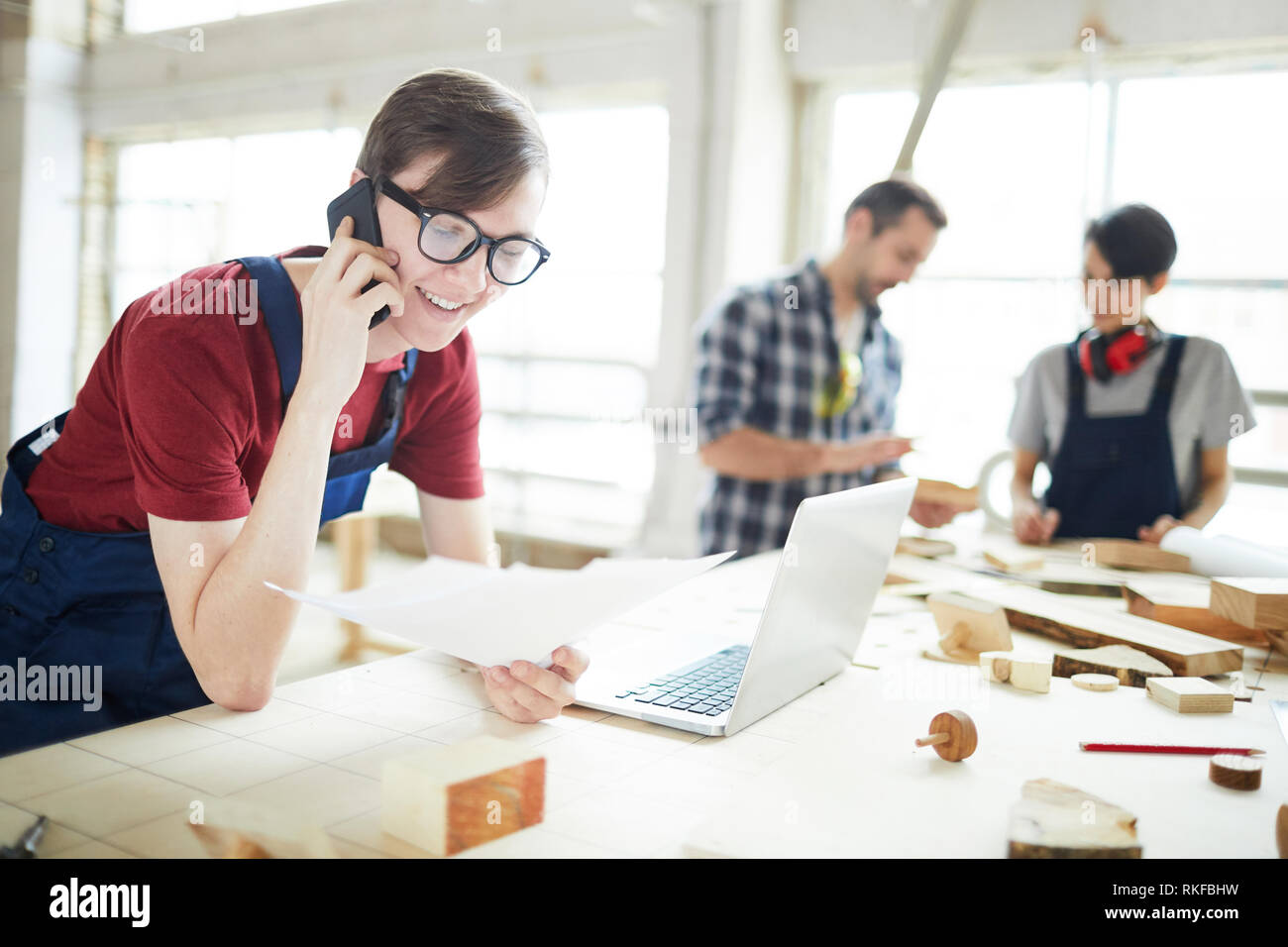Young carpenter calling customer from workshop Stock Photo - Alamy