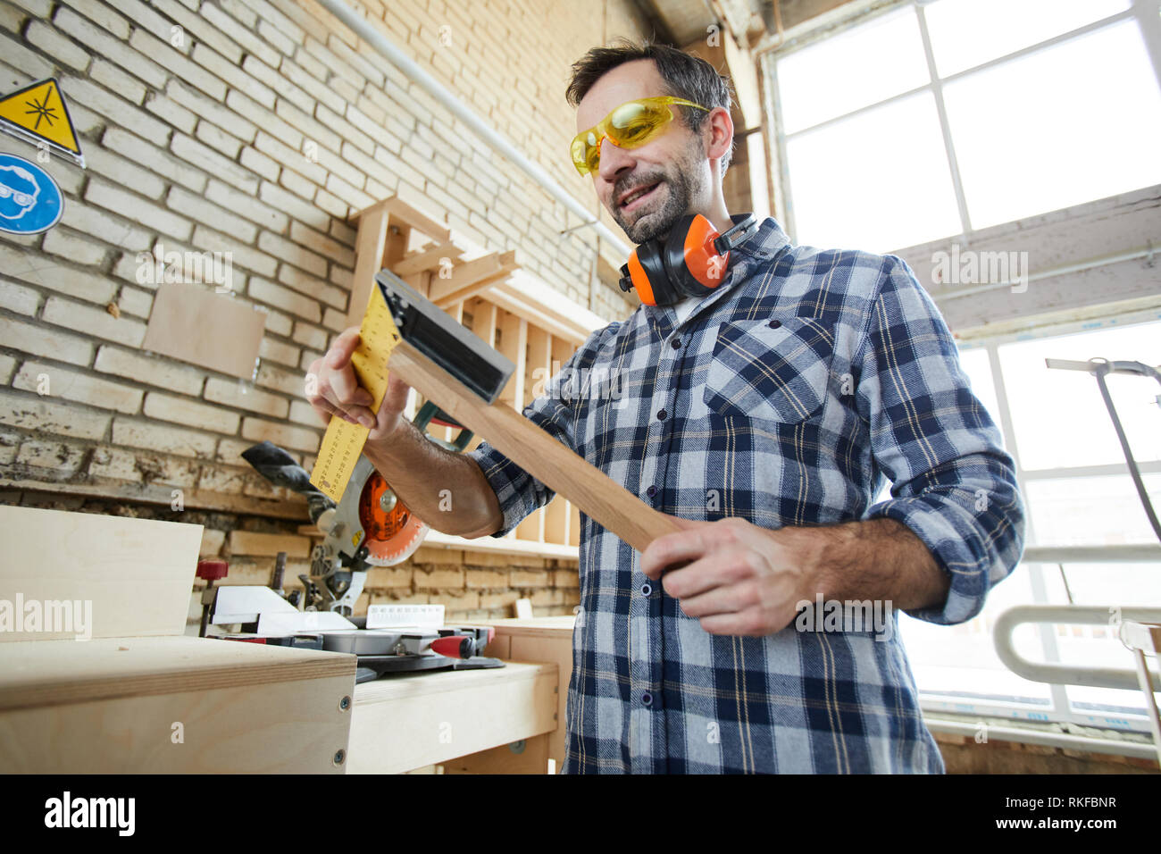 Cheerful carpenter using triangle ruler Stock Photo - Alamy