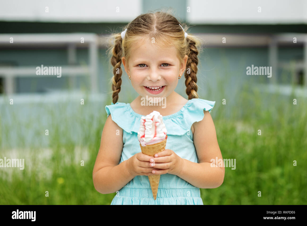 Little smiling girl is walking outdoors and eating ice cream. The ...