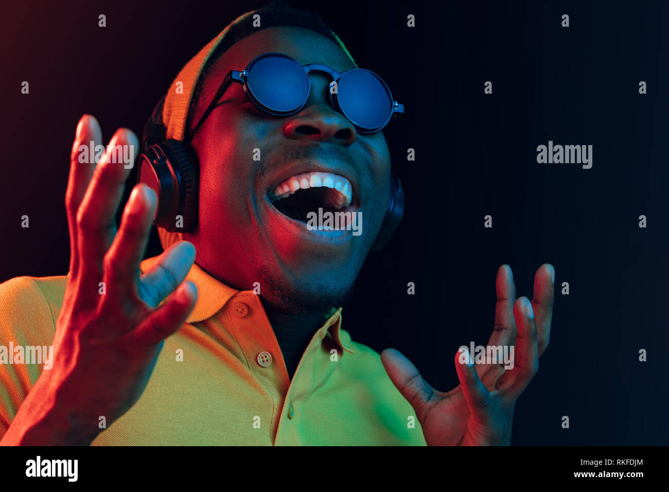 Young handsome serious sad hipster man in sunglasses listening music ...