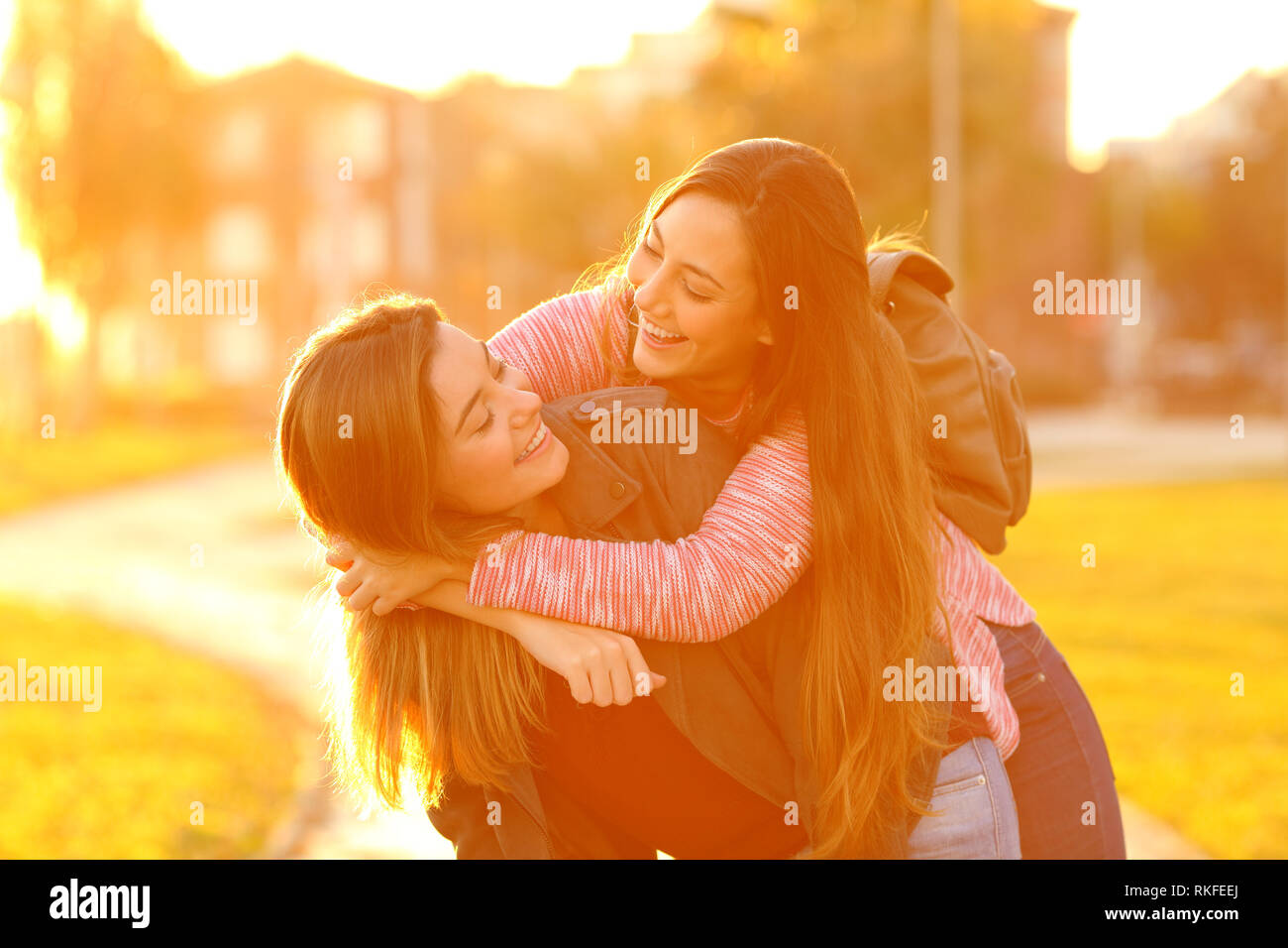 Two funny friends joking piggybacking in the street at sunset Stock ...