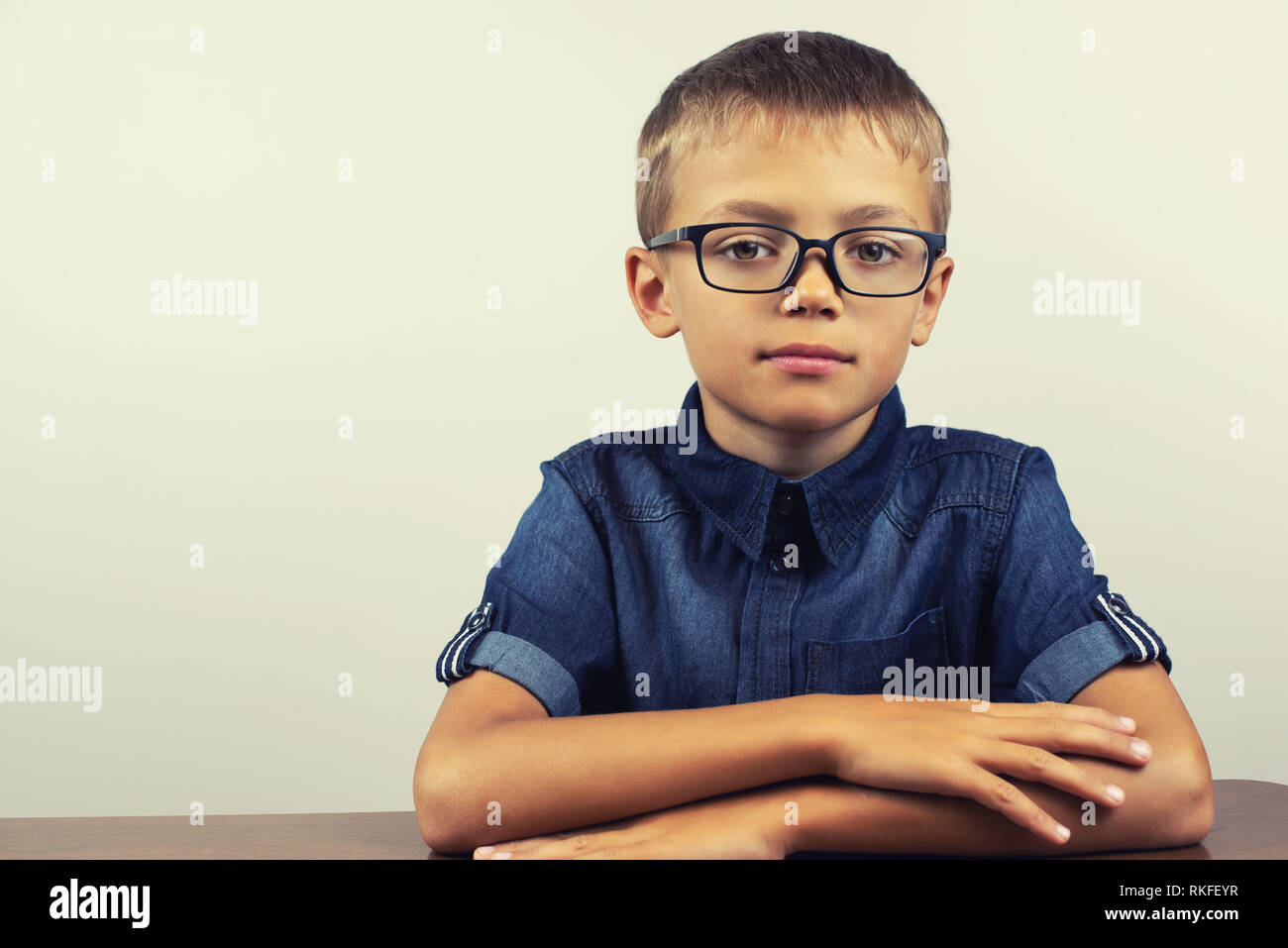 Boy student sitting at a table on a light background. Concept back to ...