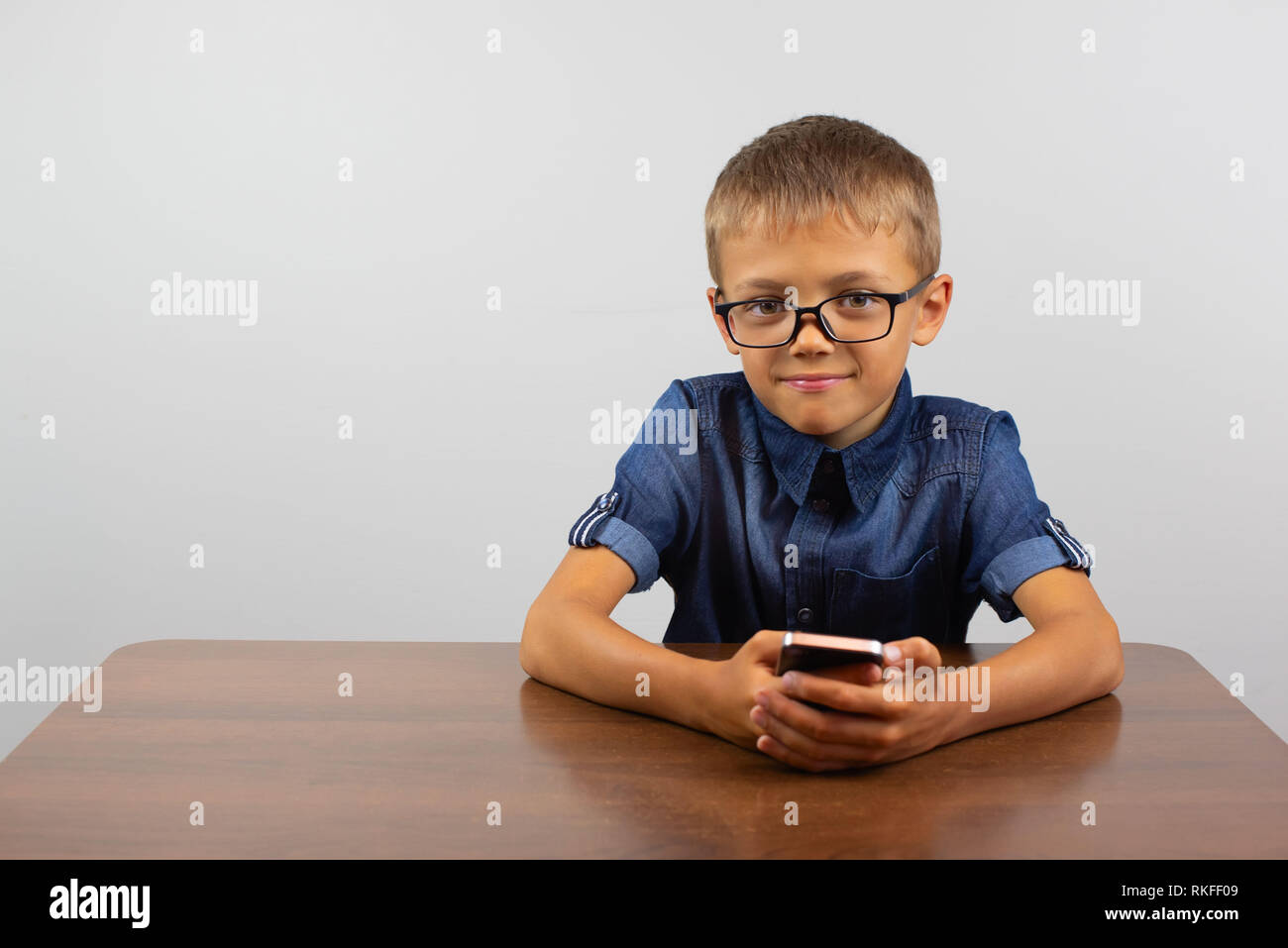 Boy student sitting at a table on a light background. Concept back to ...
