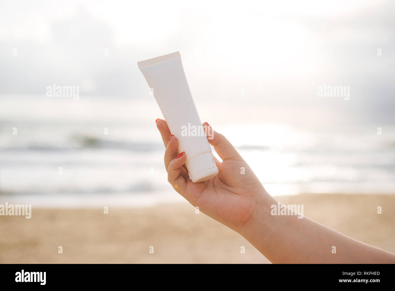Woman hand holding sunscreen on the beach with the sea in blue sky ...