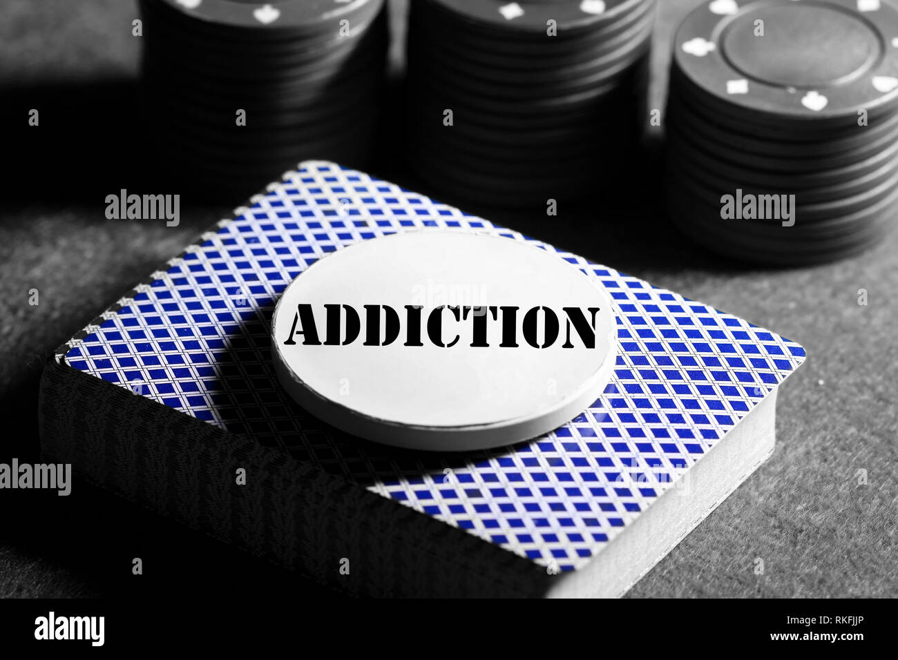 Deck of playing cards with a token on top with the word addiction and ...