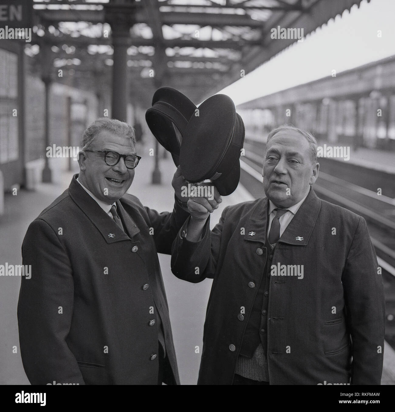 1968, two cheerful uniformed British Rail station staff, a foreman and ...