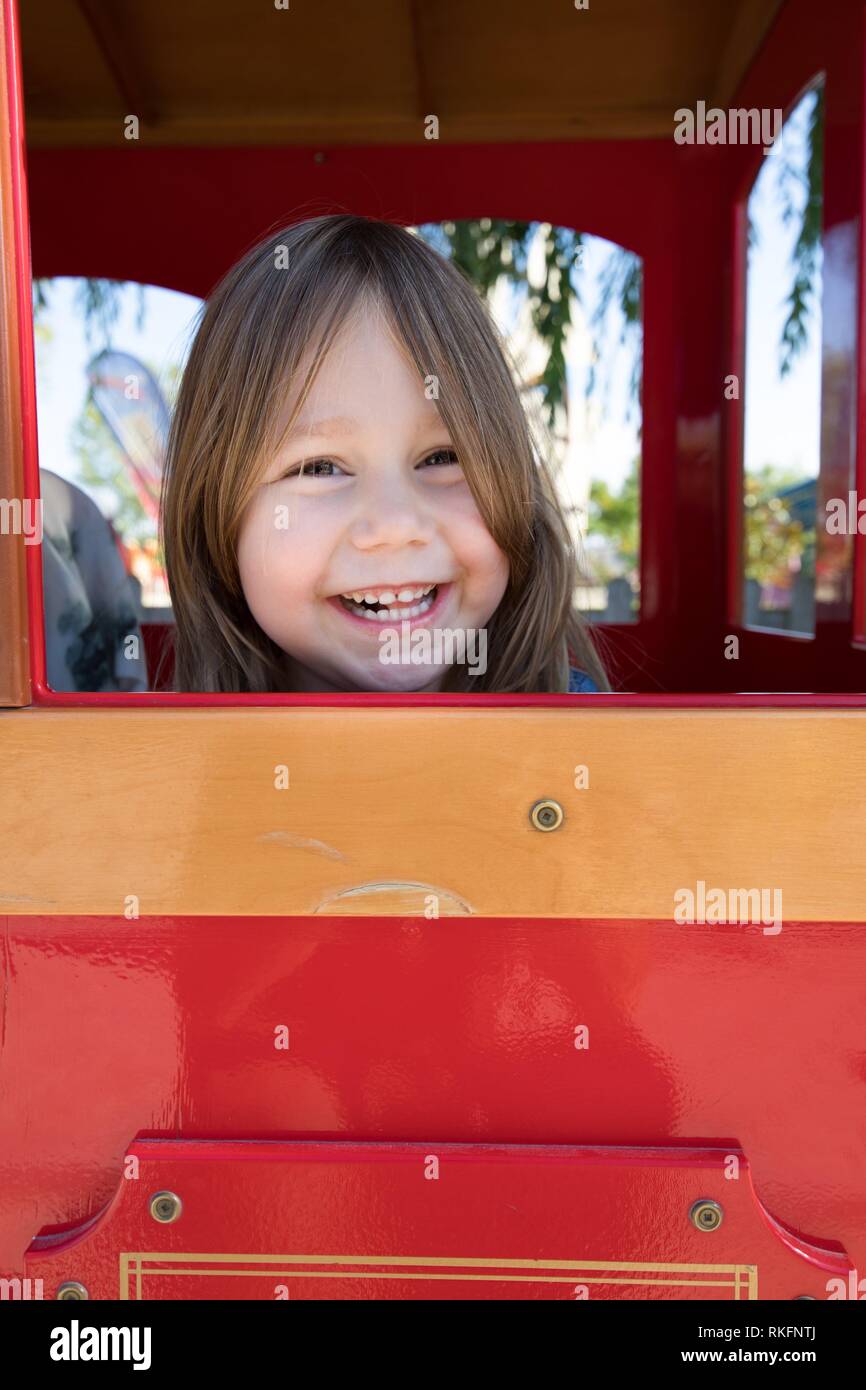 Face Of Four Years Old Blonde Girl Looking And Laughing From The Window Of Playground House In