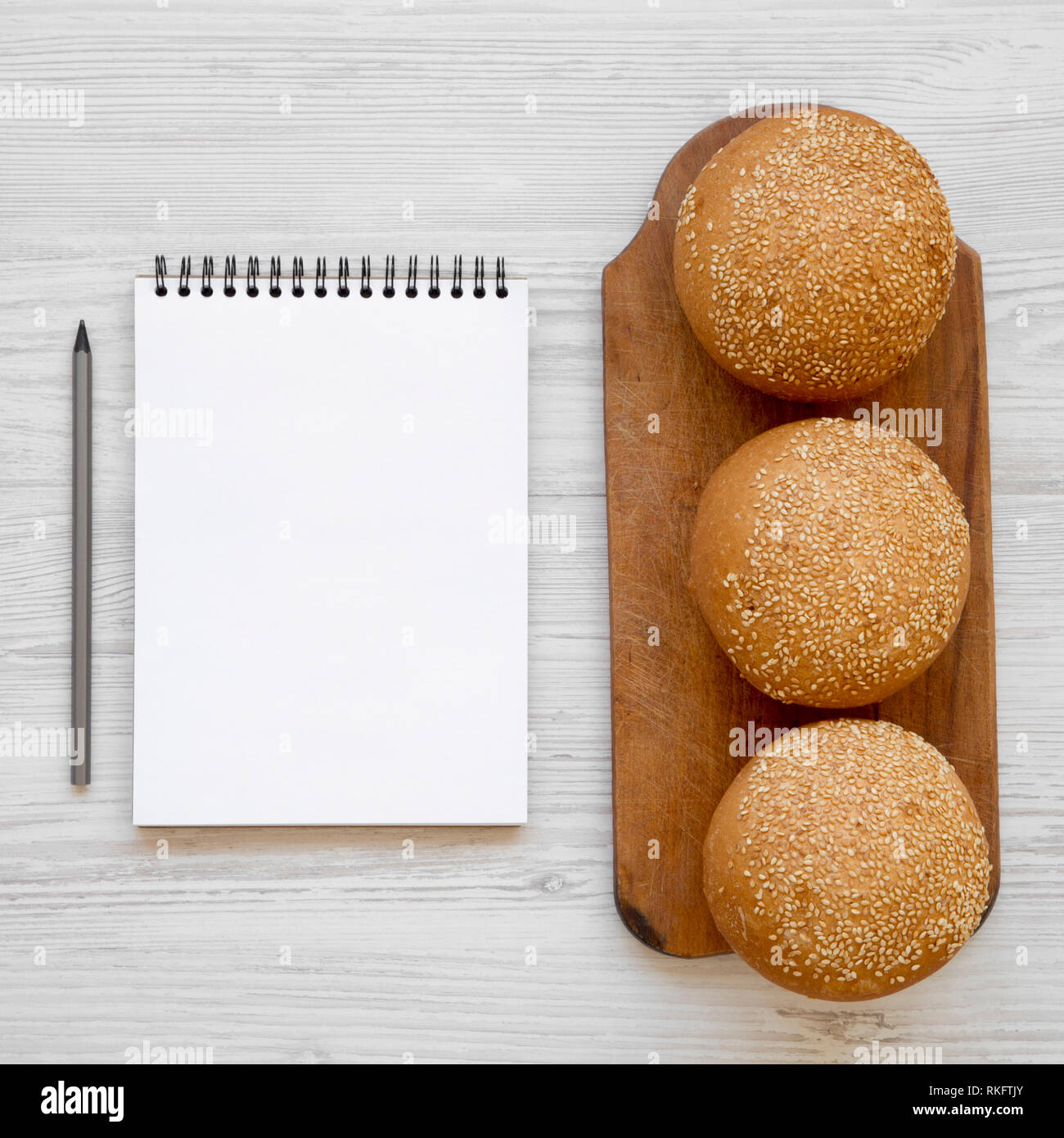 Fresh burger buns with sesame seeds on rustic wooden board, blank ...