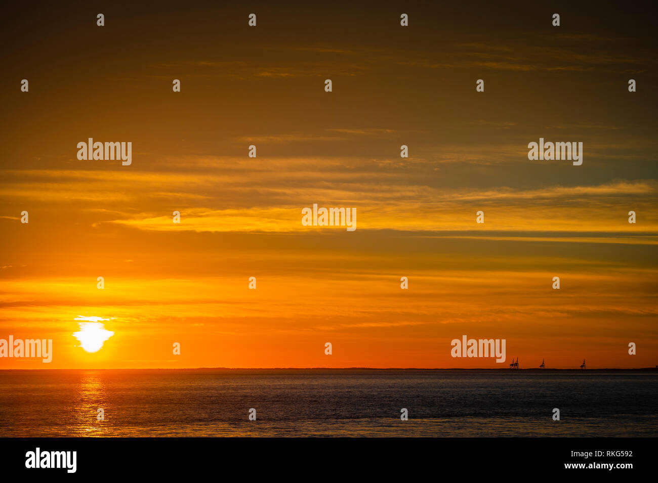 Large orange sunset as the massive sun sets into the horizon above the ...