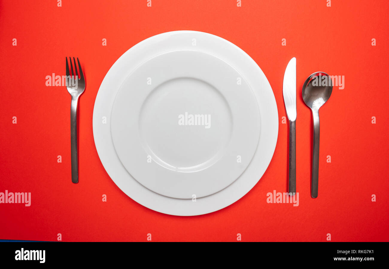Table place setting on red. Set of empty white plates and cutlery on ...
