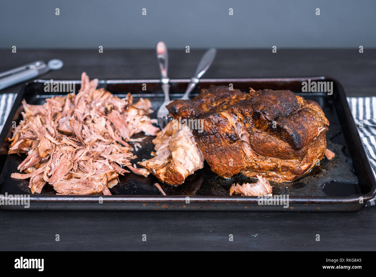 Shredding cooked pork with forks on a baking sheet Stock Photo - Alamy